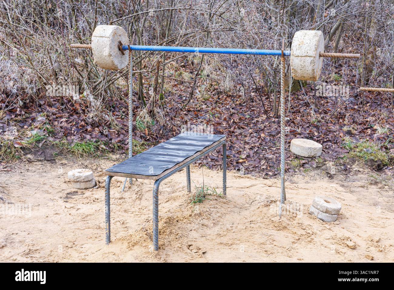 A barbell made of rebar and concrete and a bench press. An improvised ...