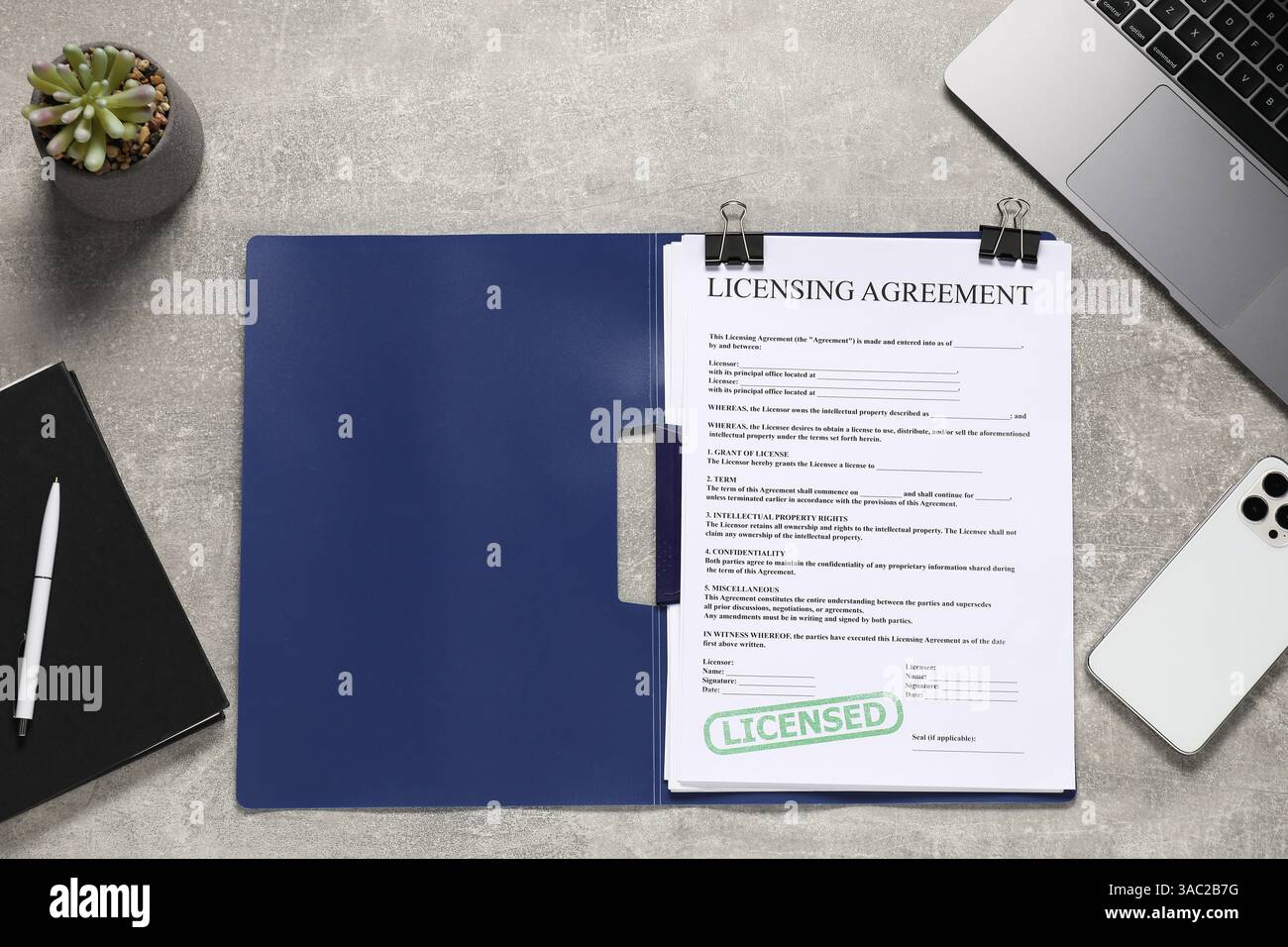 Licensing agreement document, stationery, laptop and smartphone on gray textured table, flat lay ...