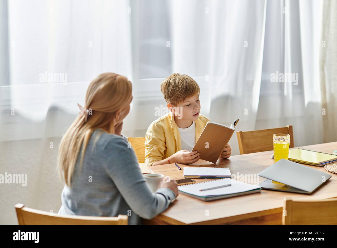 A mother enjoys a quiet moment with her son, who is deeply focused on a ...