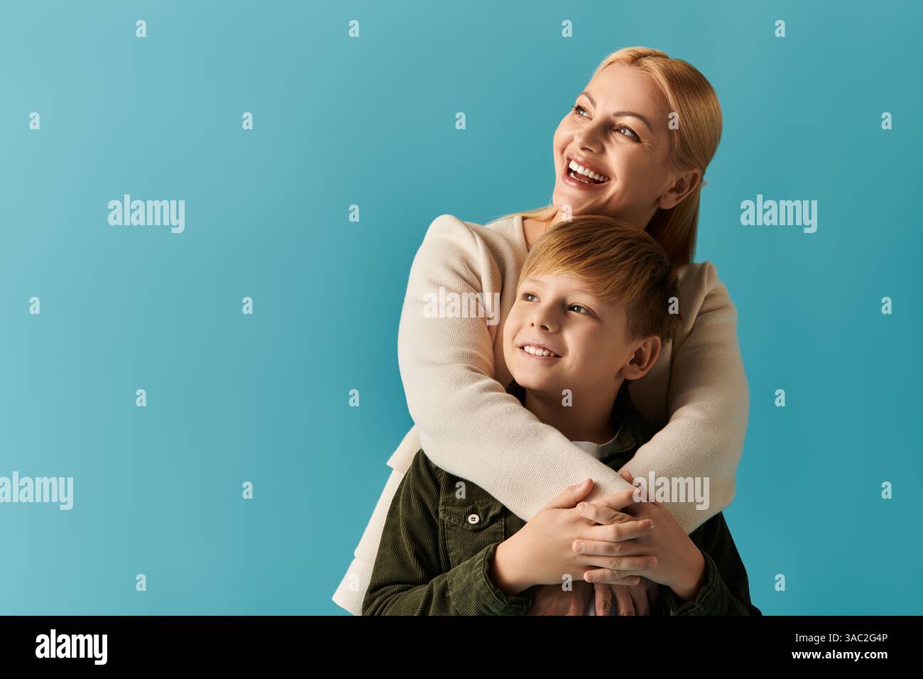 A mother joyfully hugs her son, sharing a sweet moment against a bright ...