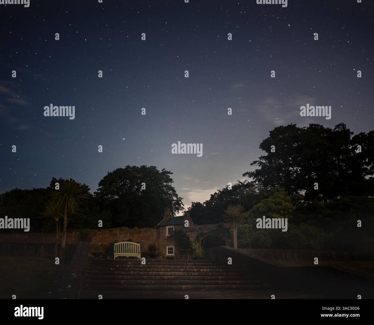 Starry Night Garden with Cottage and White Bench Stock Photo - Alamy