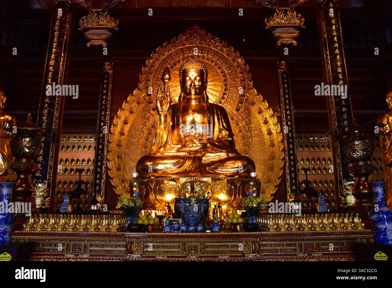 Large golden sitting Buddha statue and multiple small Buddha statues in ...