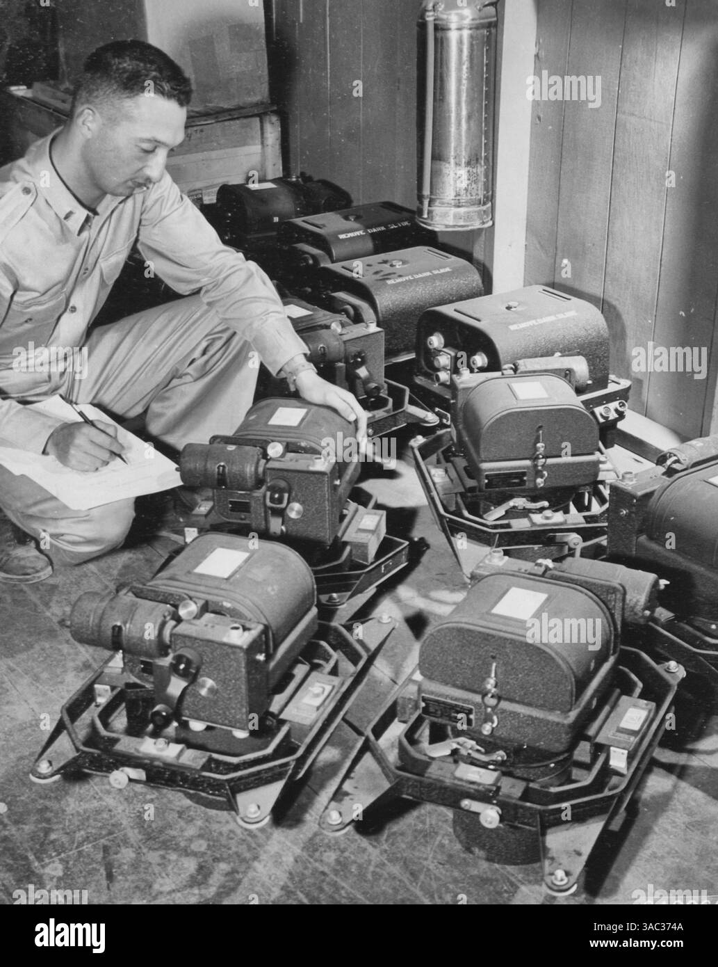 Aerial cameras being inspected before being put in B-24 Liberator ...