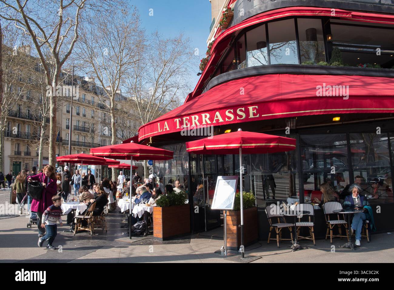 Tourists enjoy the sun outside the bar La Terrasse in central paris in ...