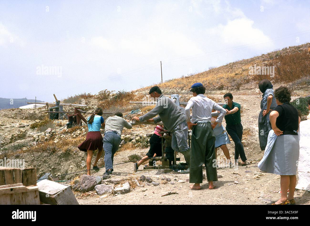 A group of people using a medieval-style capstan to haul goods up a ...