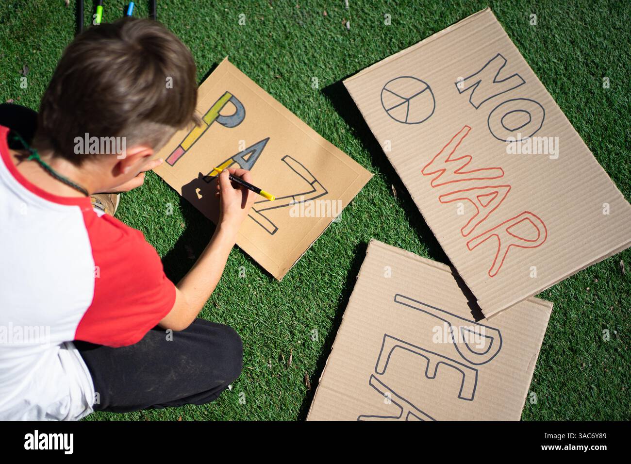 Child making peace posters on a green lawn, advocating for no war Stock ...
