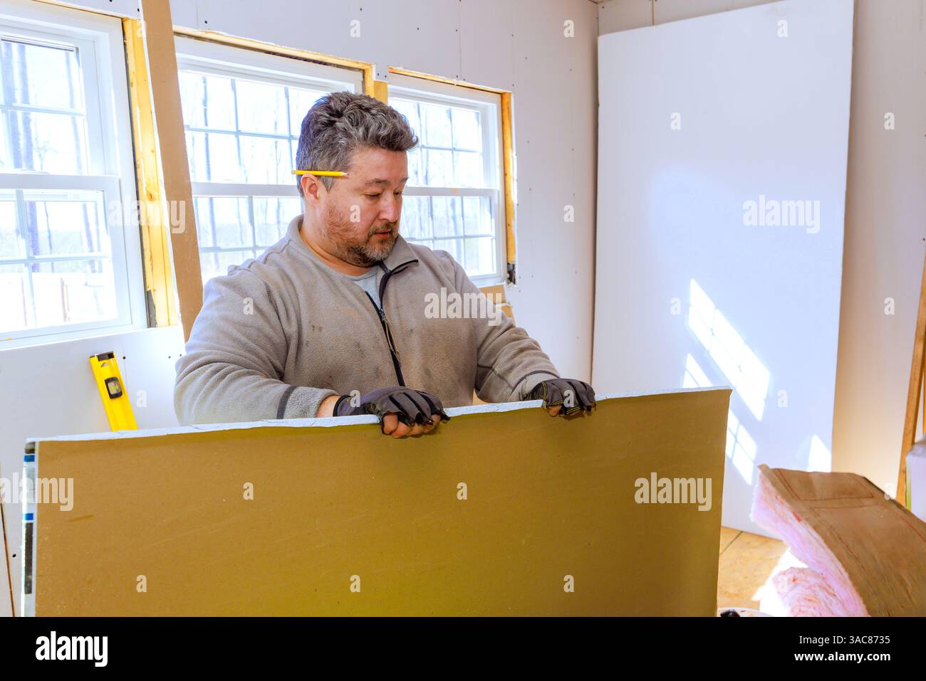 Construction worker carefully handling drywall sheets while renovating ...