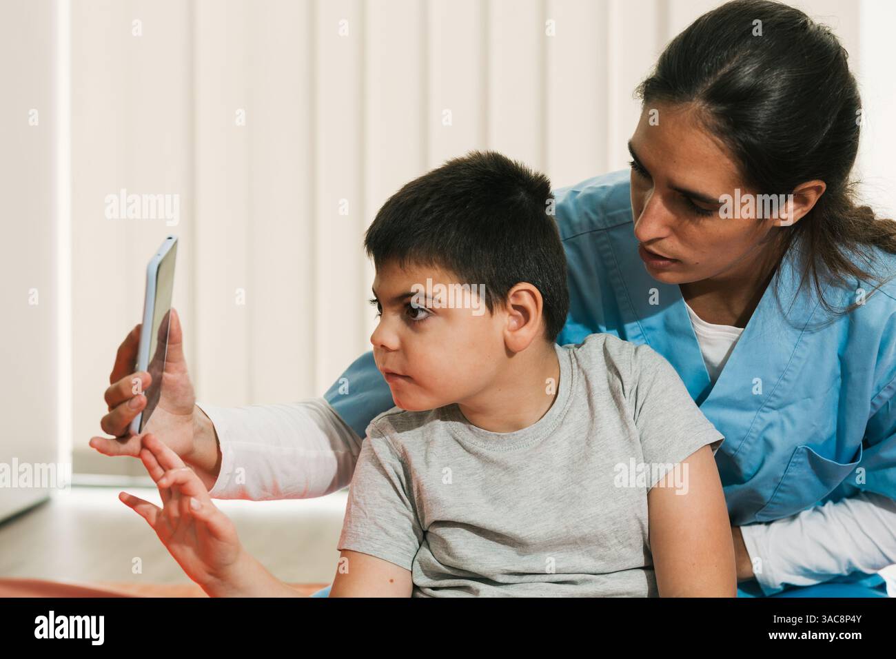 Physiotherapist helping child with cerebral palsy using smartphone for ...