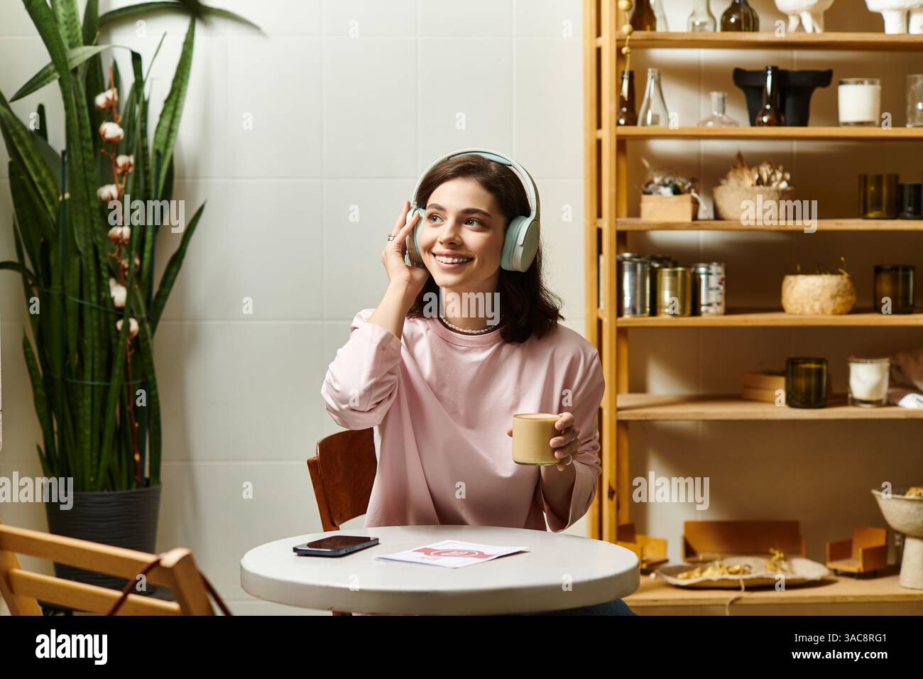 A cheerful young woman sips her coffee and listens to music in a modern ...