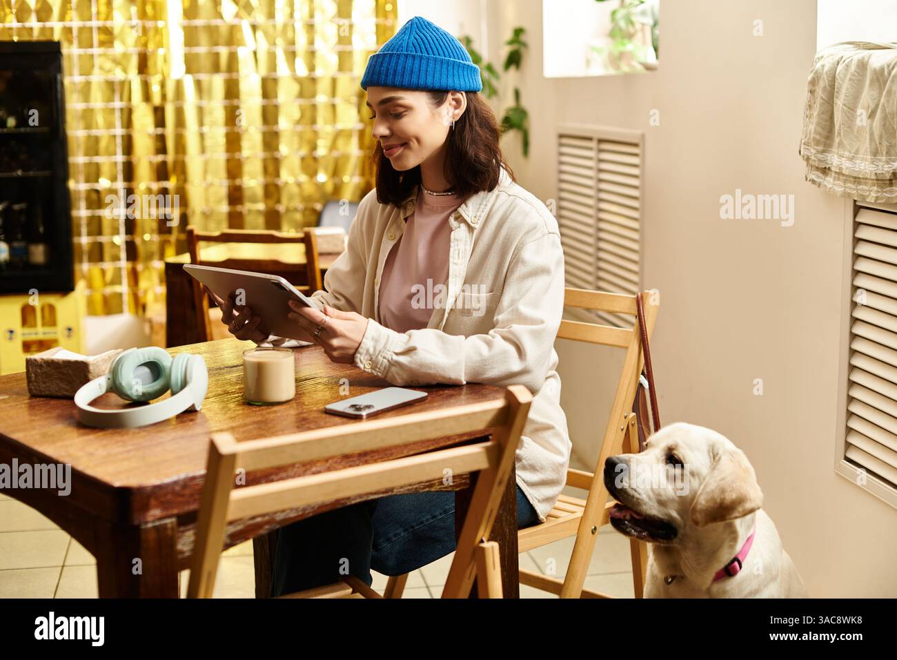 Bright and welcoming cafe where a young woman relaxes with her labrador ...