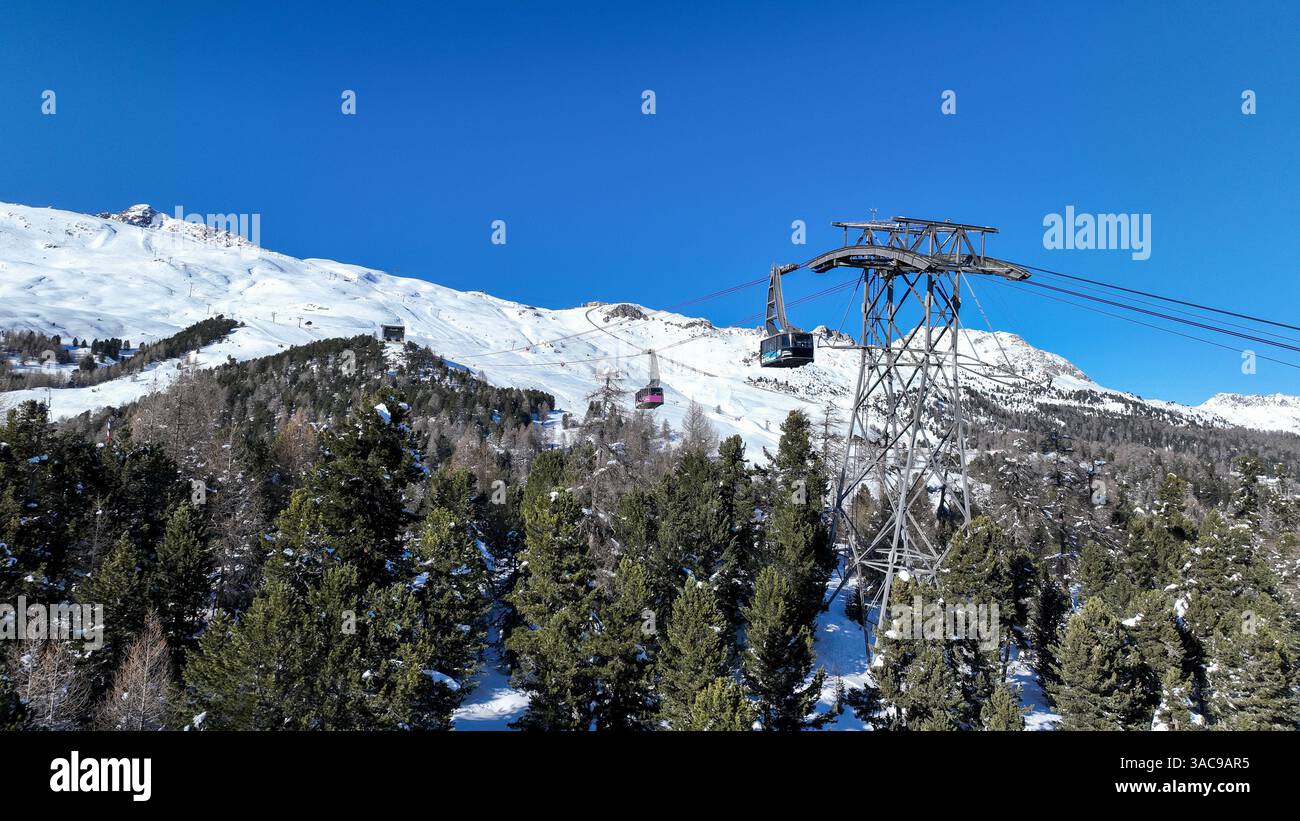 Two gondolas pass by in the ski area Engadin in the mountains. Two ...