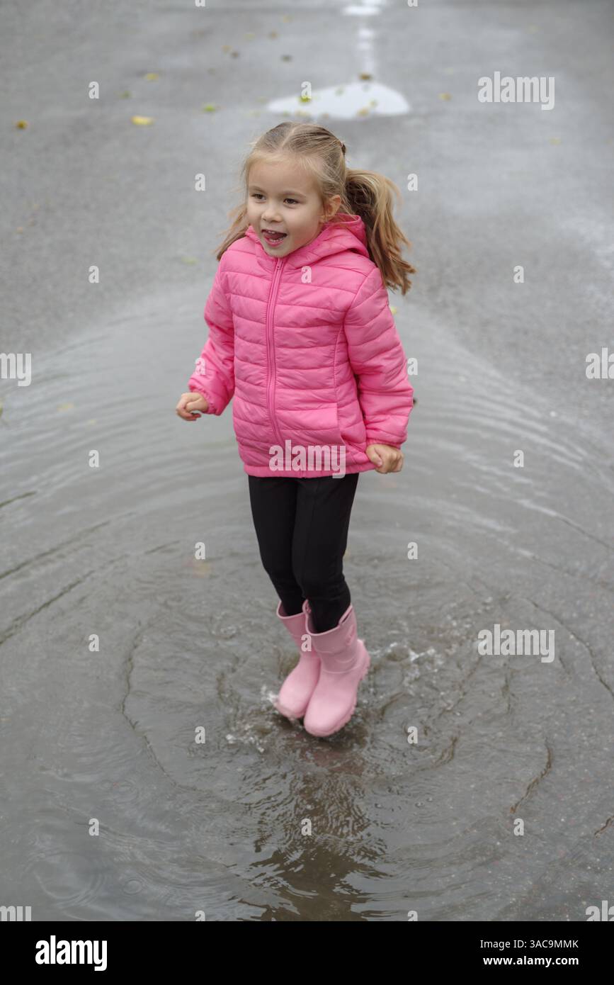 Child girl in rain boots jumps in a deep puddle Stock Photo - Alamy
