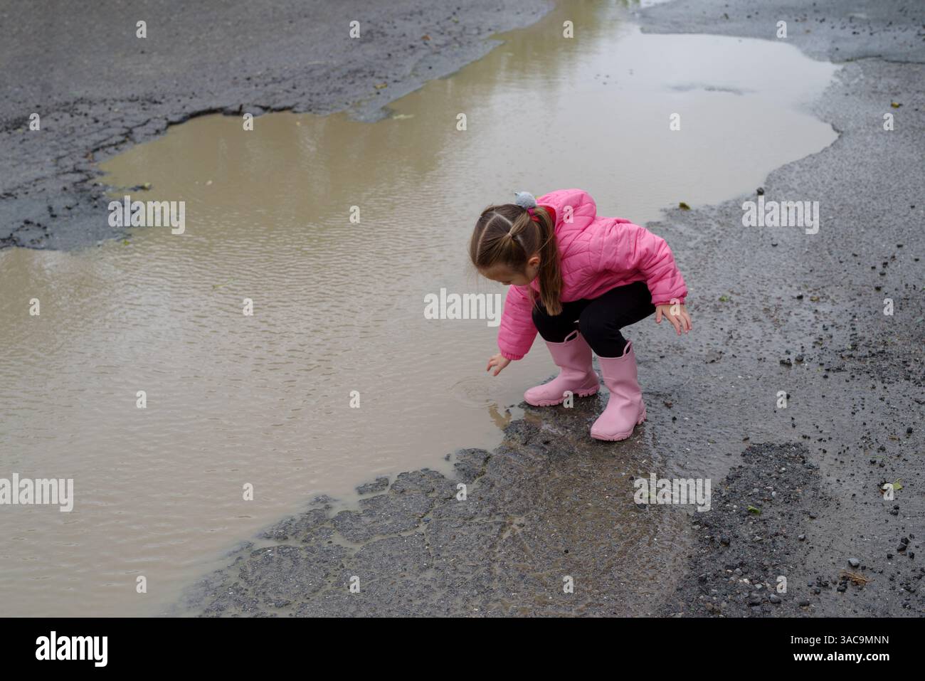 Cute little girl stepped in a puddle after rain has rubber boots and ...