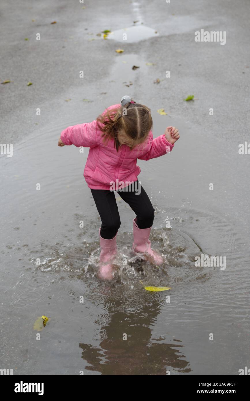 Child girl in rain boots jumps in a deep puddle Stock Photo - Alamy