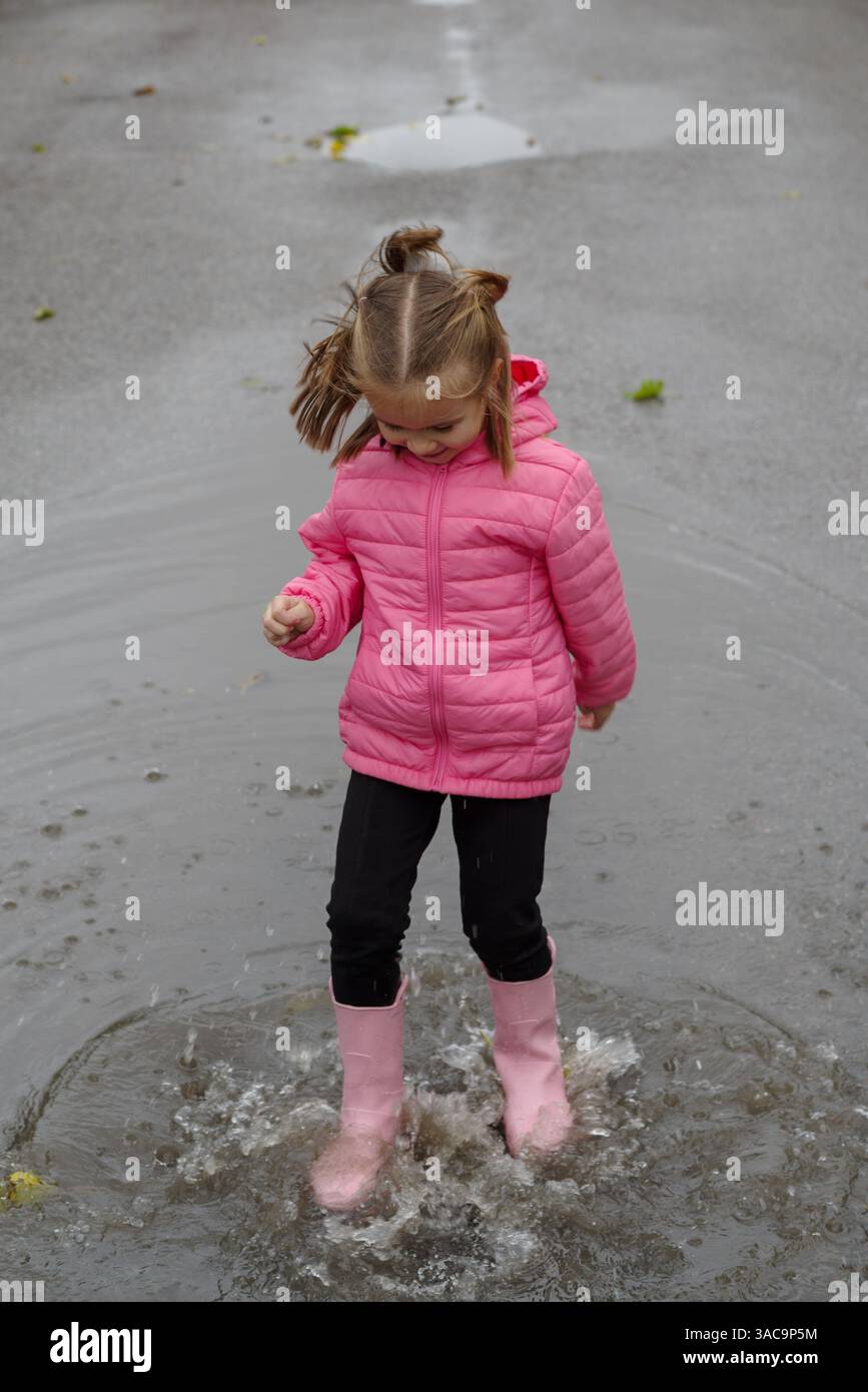 Child girl in rain boots jumps in a deep puddle Stock Photo - Alamy