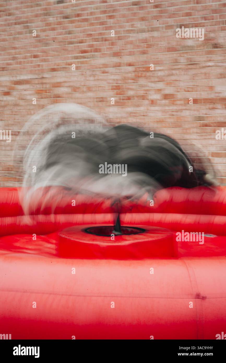 Children enjoy a spinning game on a bright red inflatable, laughing and ...