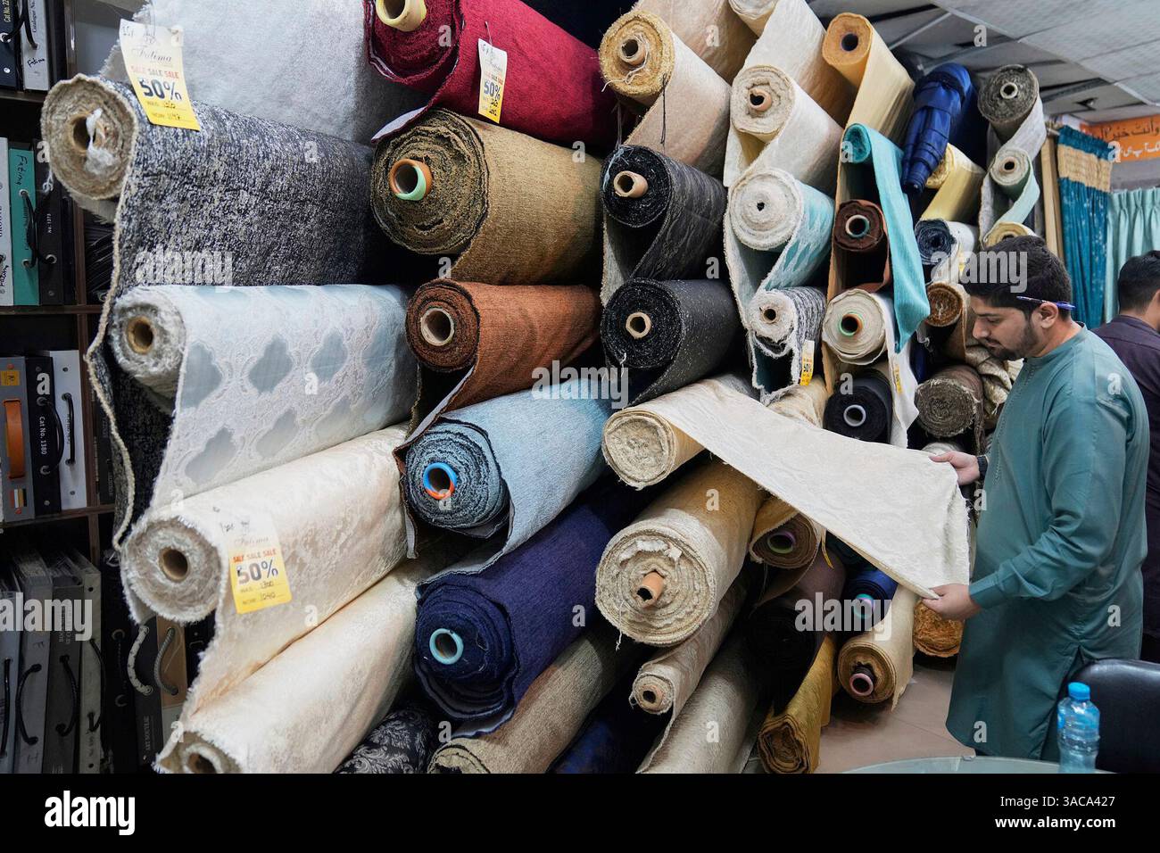 A vendor displays linen sofa fabric in a house linens store at a market ...