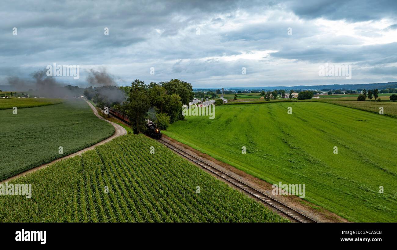 A vintage steam train moves along a meandering railway, surrounded by ...