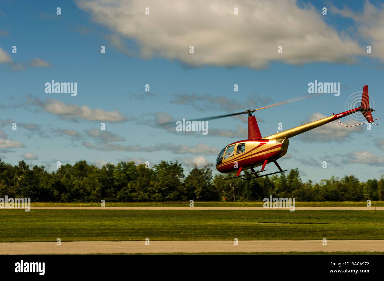 single private helicopter lifting off a runway into a lightly clouded ...