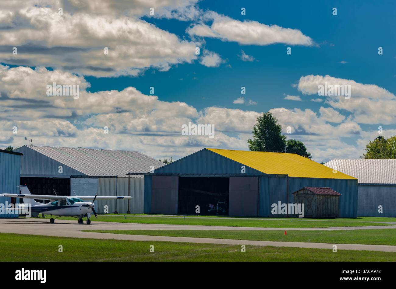 Small single engine plane in front of hangar building with a yellow ...