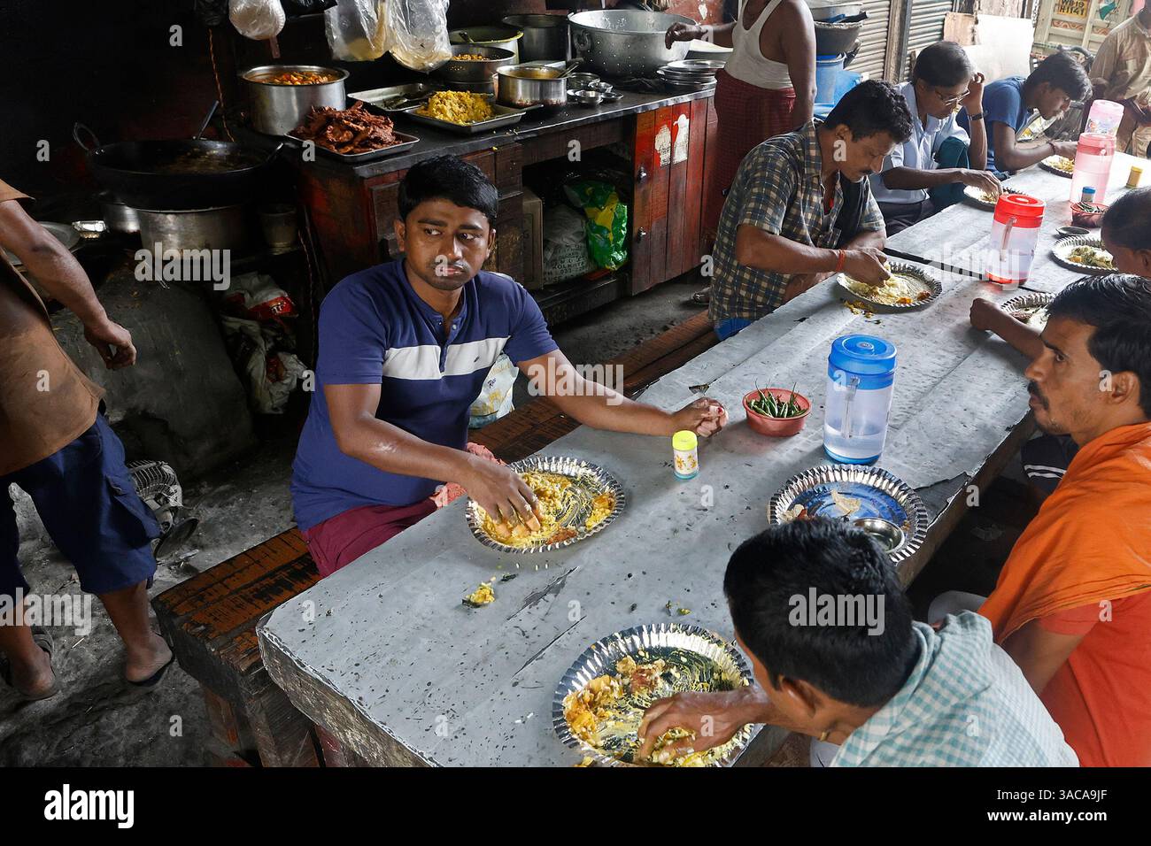 People eating vegetarian thali at a food stall in Kolkata, West Bengal ...