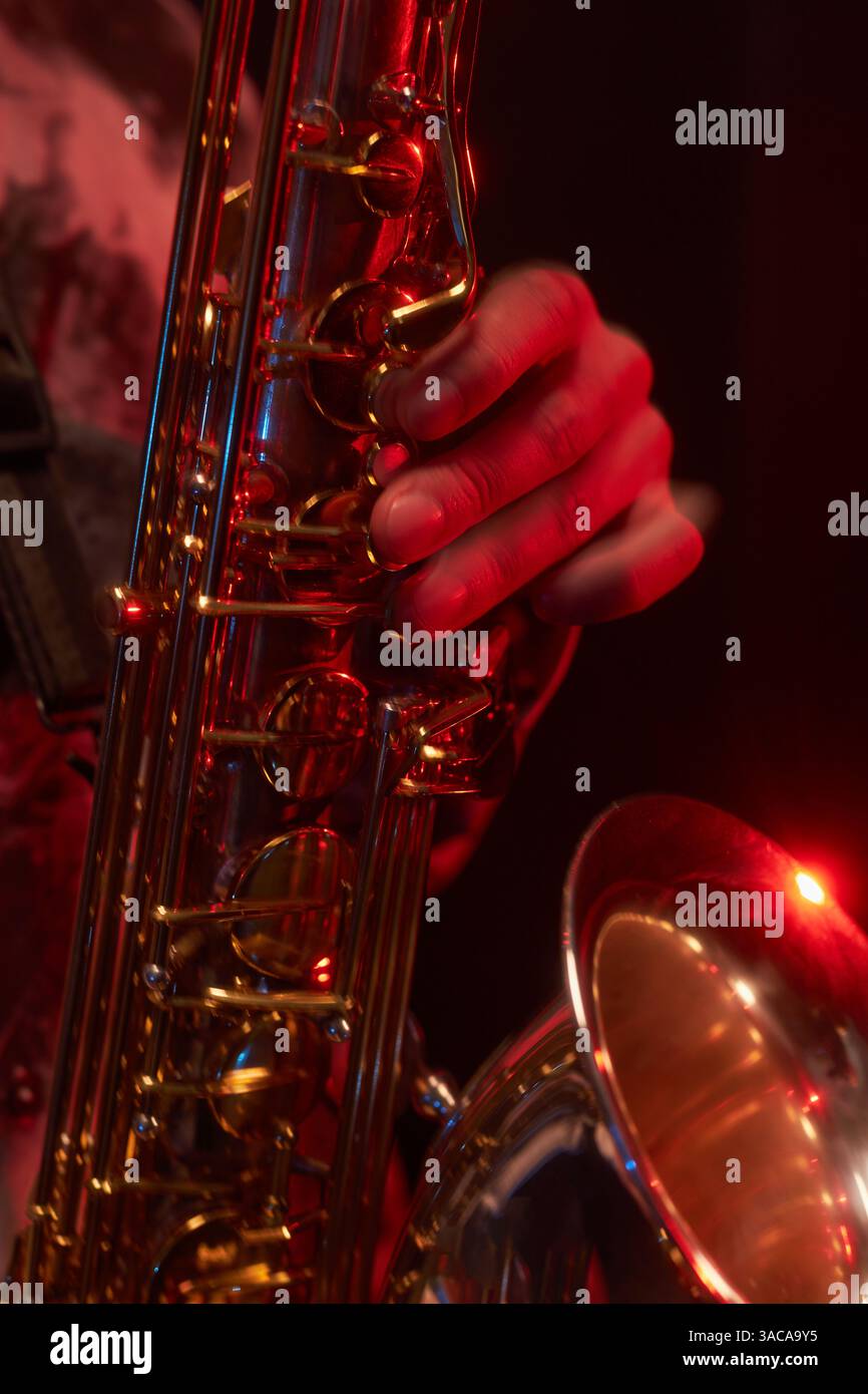 Vertical close up shot of male saxophonist playing enchanting jazz ...