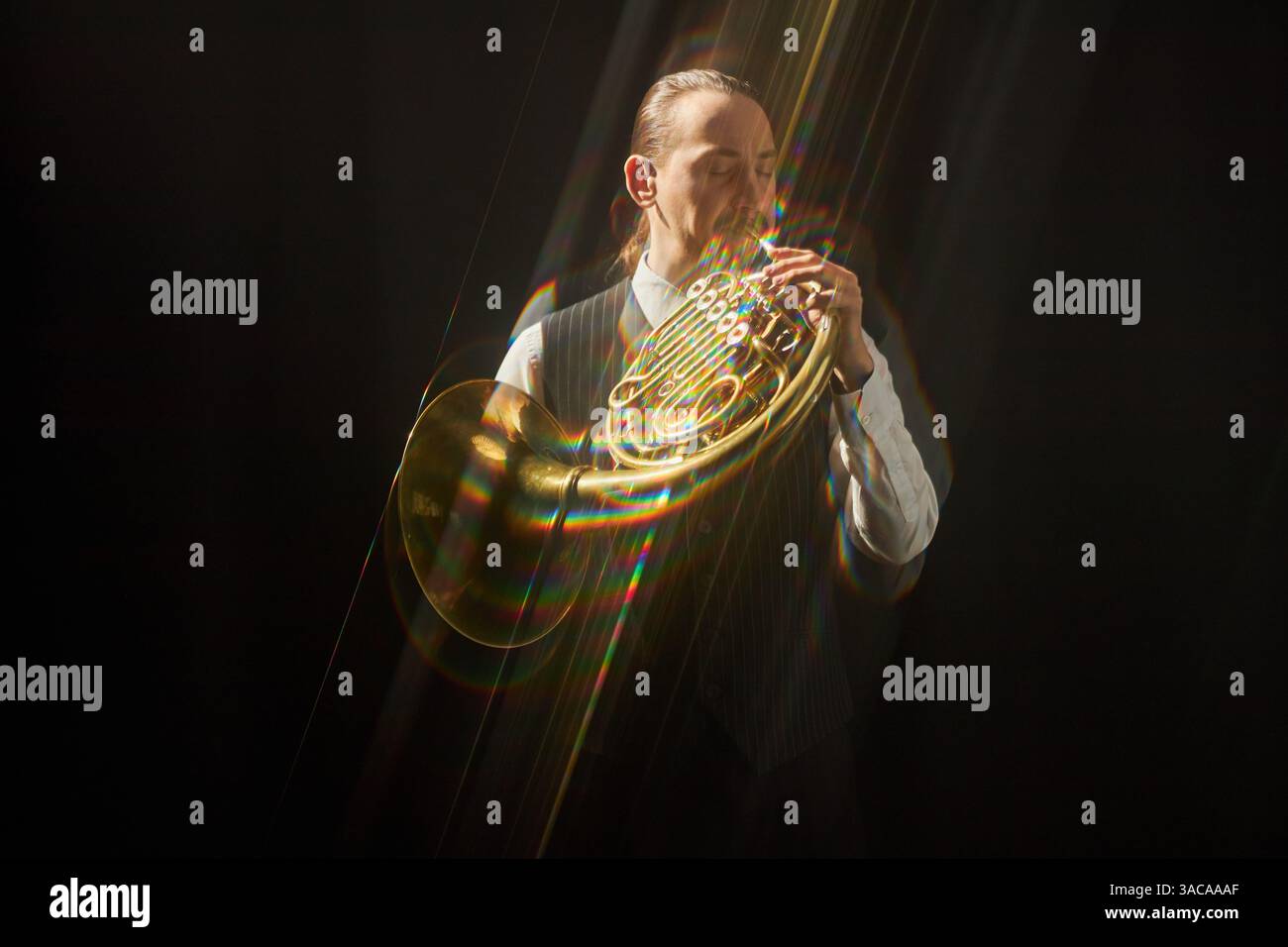 Medium shot of passion driven male musician playing French horn ...