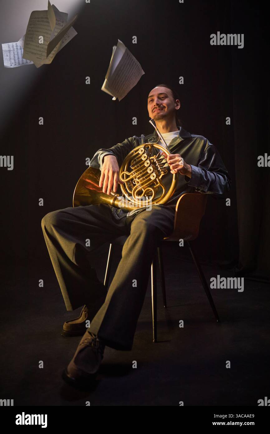 Vertical shot of professional male musician sitting in chair with ...
