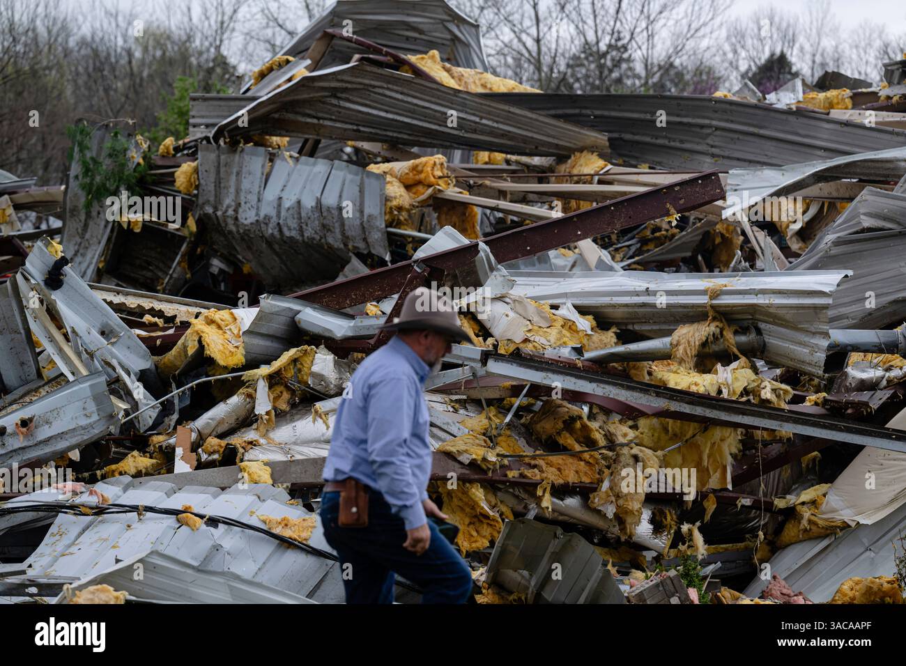 A man wearing a cowboy hat looks on at the destroyed KEP Electric ...