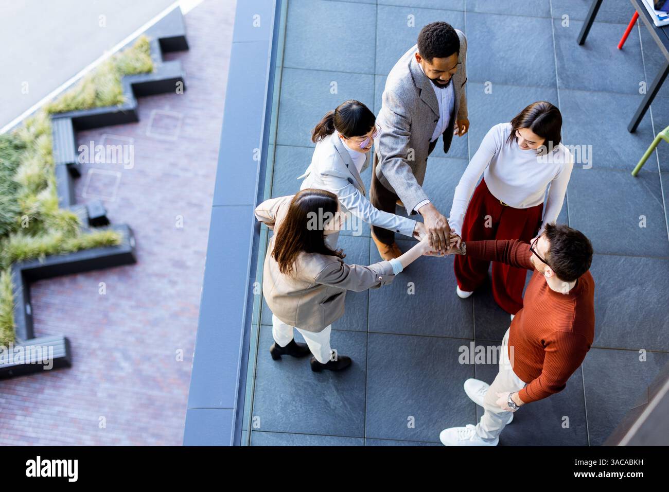 Five friends engage in an enthusiastic group handshake, showcasing ...