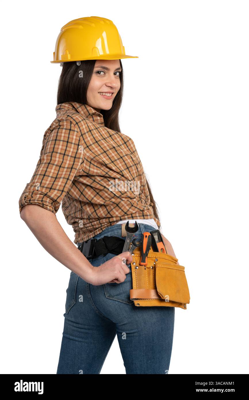 Portrait of smiling female construction worker wearing a yellow helmet, plaid shirt, jeans, and ...
