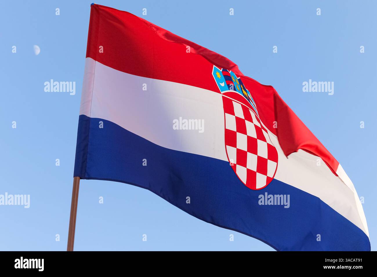 The vibrant Croatian flag flies high under the clear blue sky ...