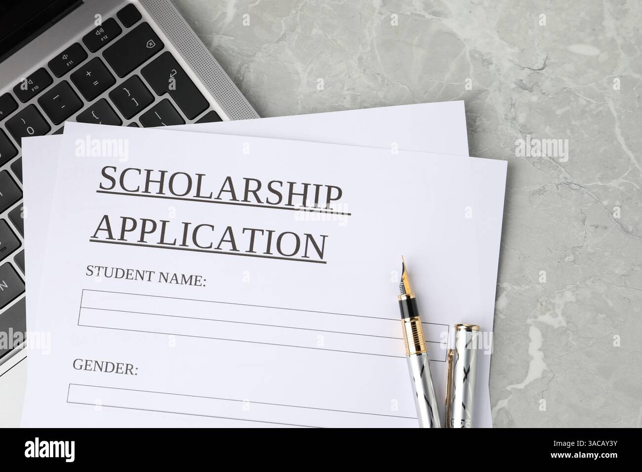 Scholarship application form, fountain pen and laptop on grey marble ...