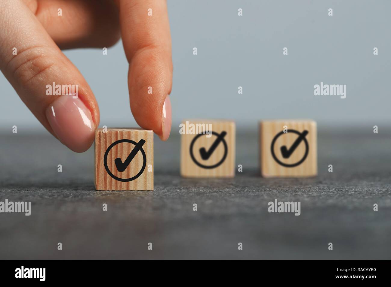 Approved. Woman touching cube with check mark on grey table, closeup ...