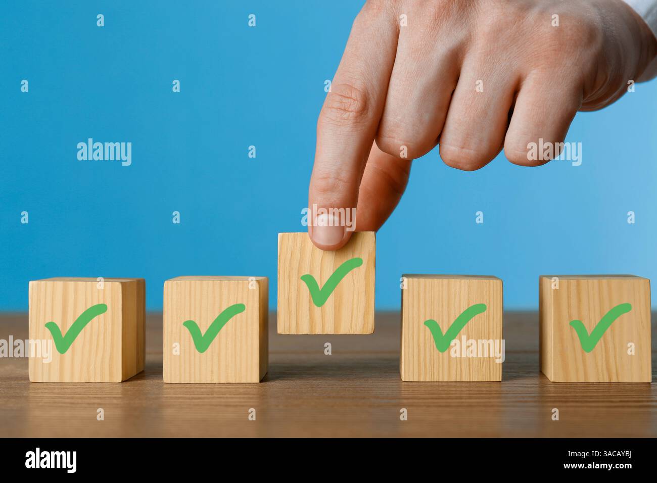 Approved. Man taking cube with check mark on blue background, closeup ...