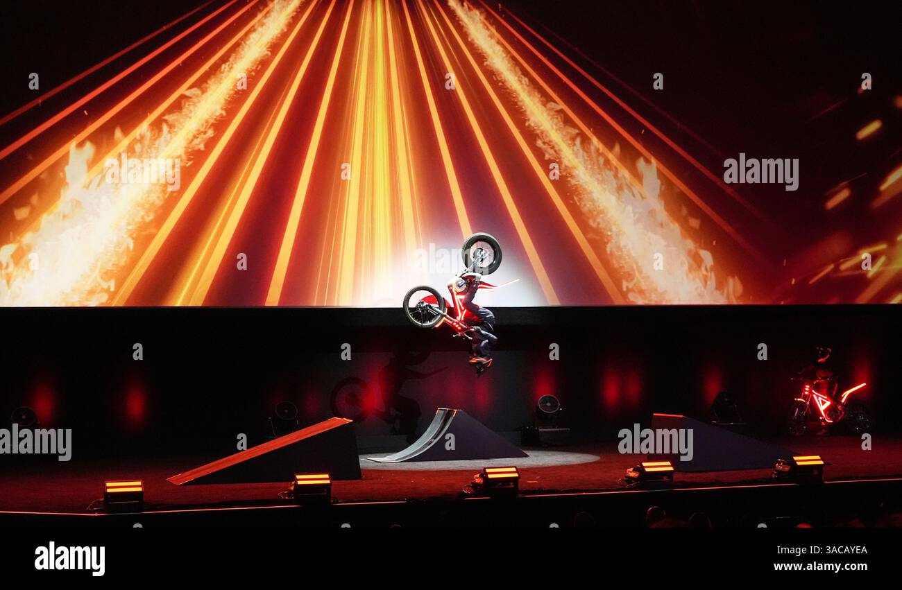 A motorcycle jumper performs a stunt onstage at the opening of the ...