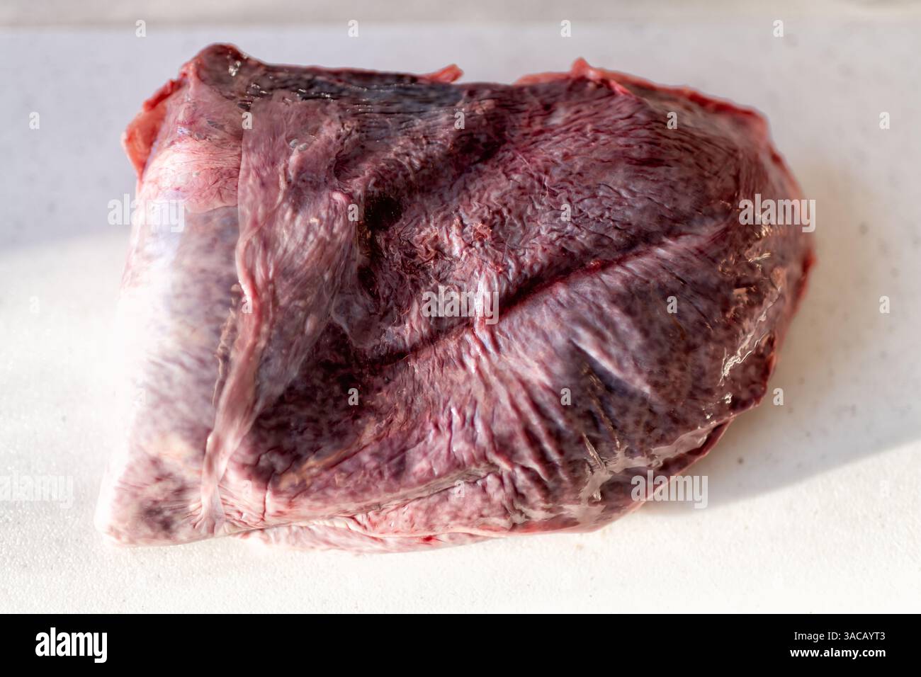 Cow beef spleen organ meat raw uncooked on cutting board in kitchen ...