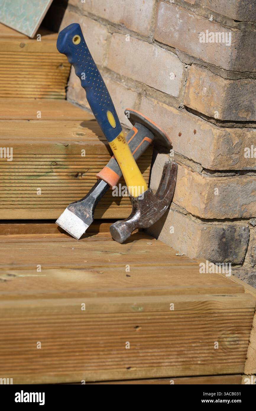Claw hammer and bolster chisel against a brick wall and decking Stock ...