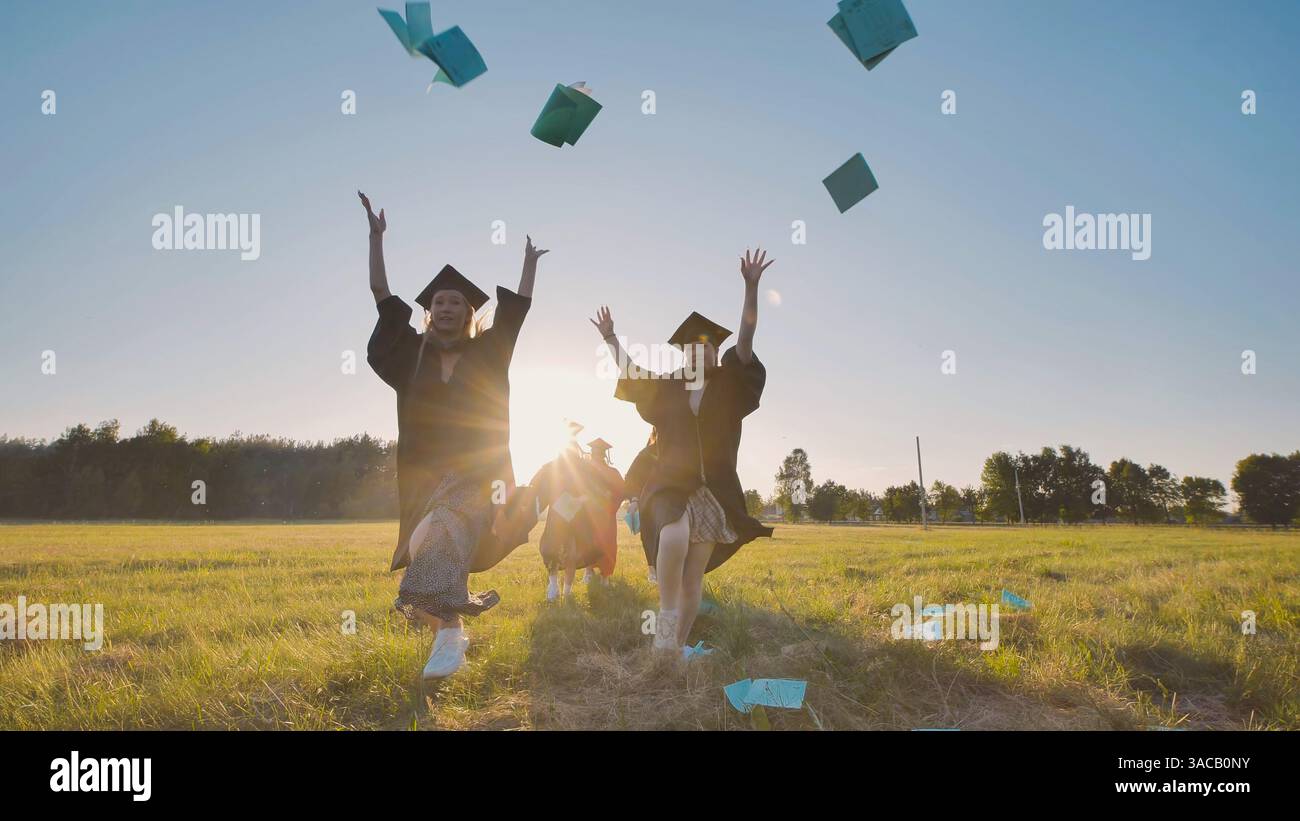 Happy graduates tossing their books in the air and celebrating their ...