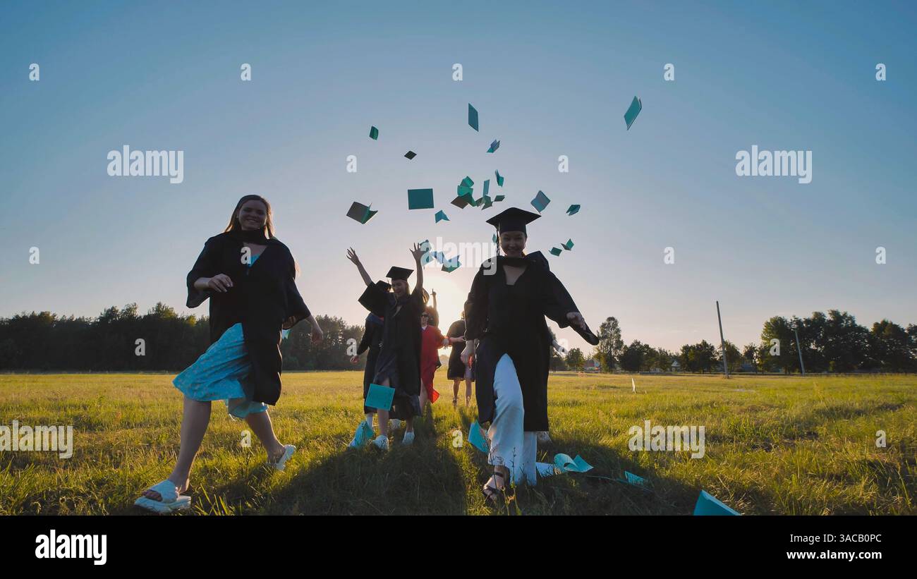 Joyful graduates in academic attire toss their caps in the air to ...