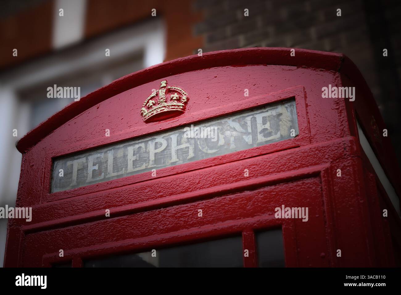 Iconic British red telephone box with golden crown emblem, situated ...
