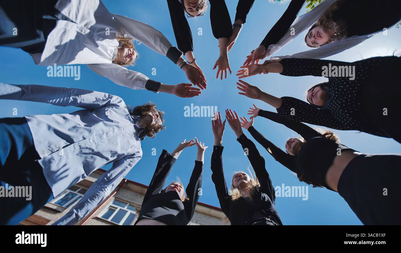 Students joining hands in a circle, celebrating their school day with ...