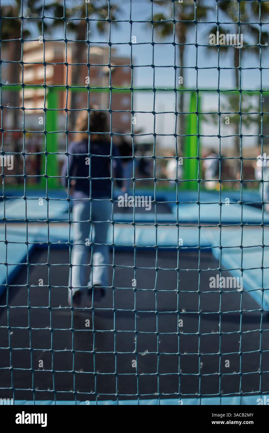 Girl jumping on trampolines surrounded by safety nets Stock Photo - Alamy