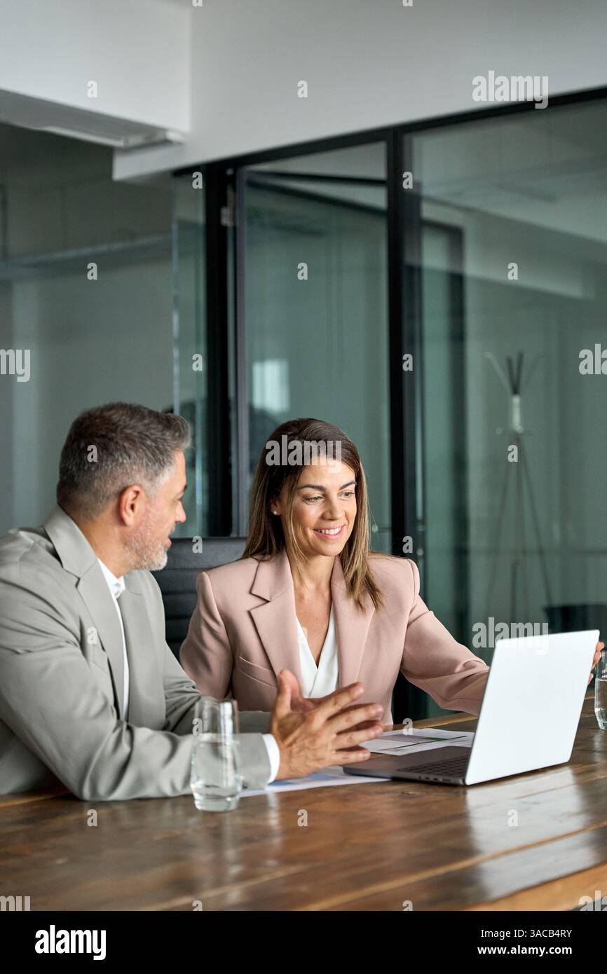 Two executive managers working on laptop at office meeting. Vertical ...