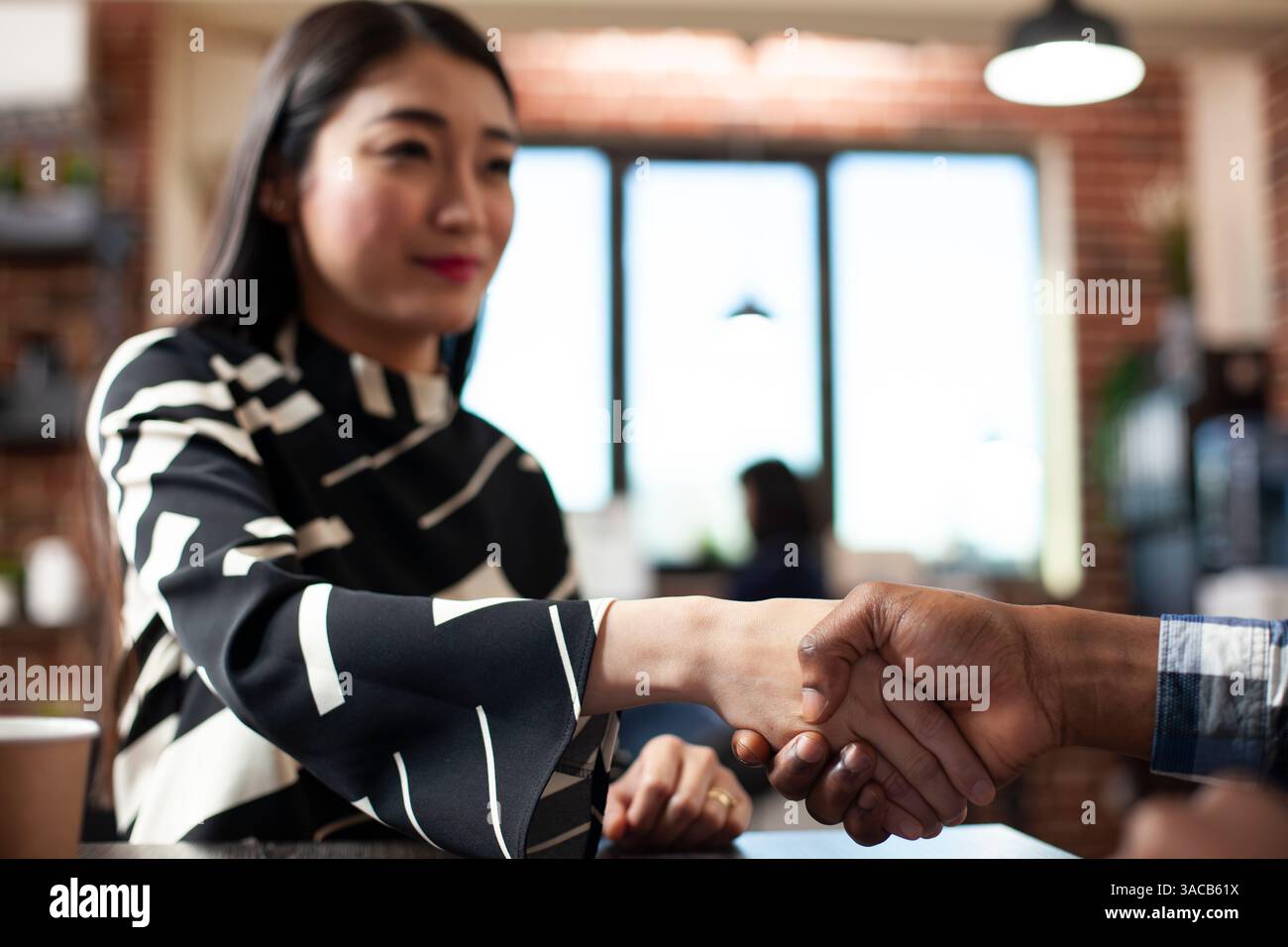 Closeup of asian woman giving a handshake to african american person ...