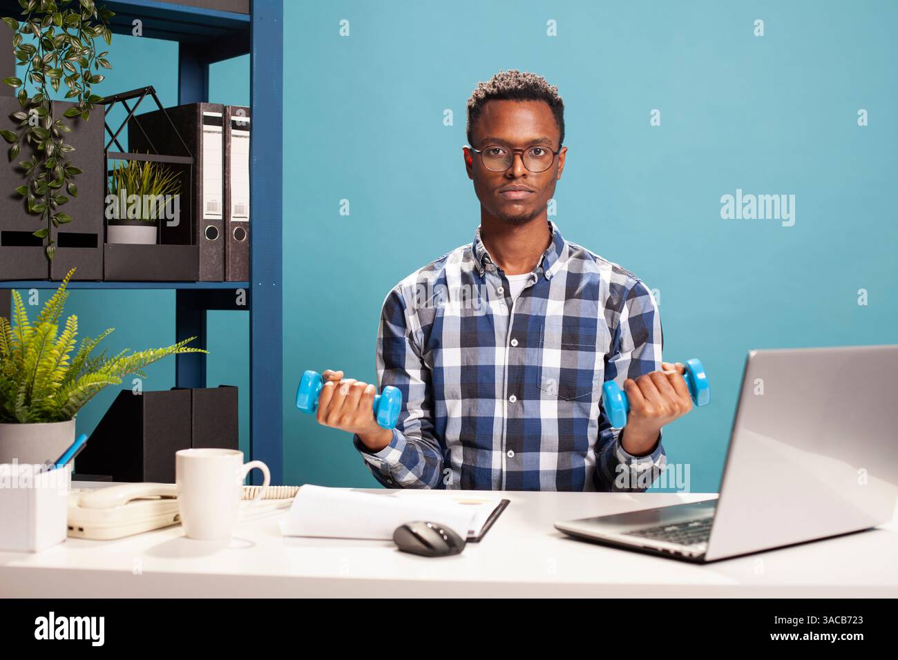 African american businessman seated at office desk, doing arms workout ...