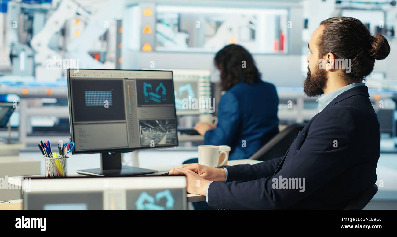 Photovoltaics factory worker using PC to monitor performance of robot ...