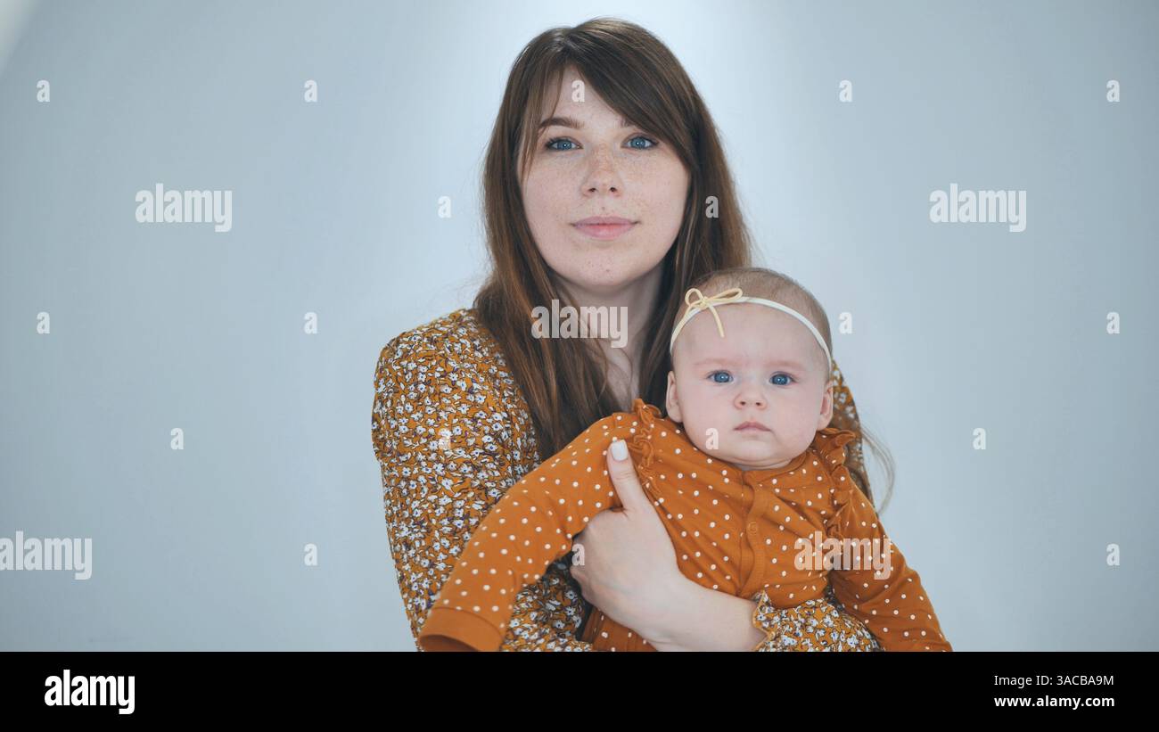 Mother and baby girl wearing matching patterned outfits are posing ...