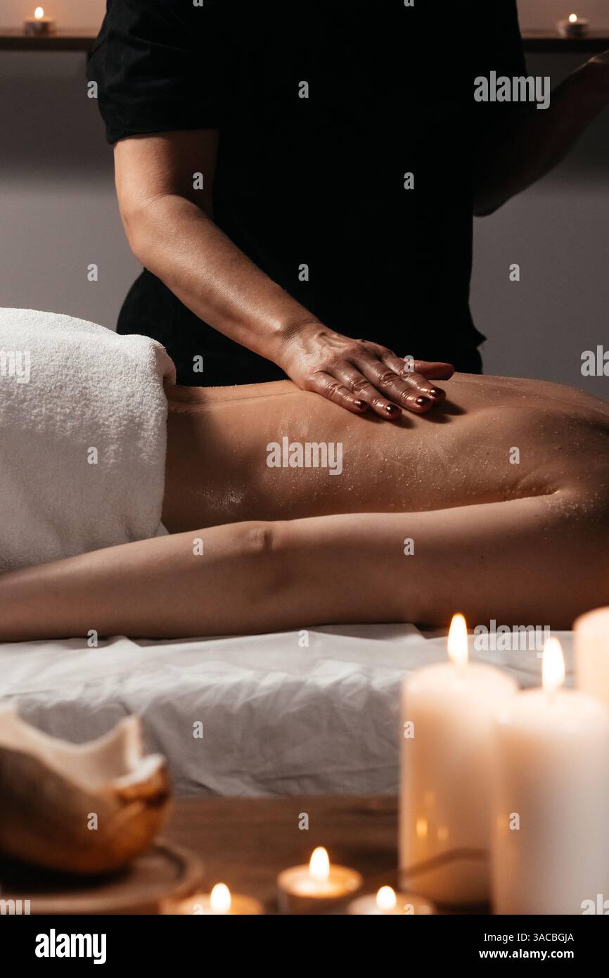 Relaxed woman lying on massage table while massage therapist massages ...