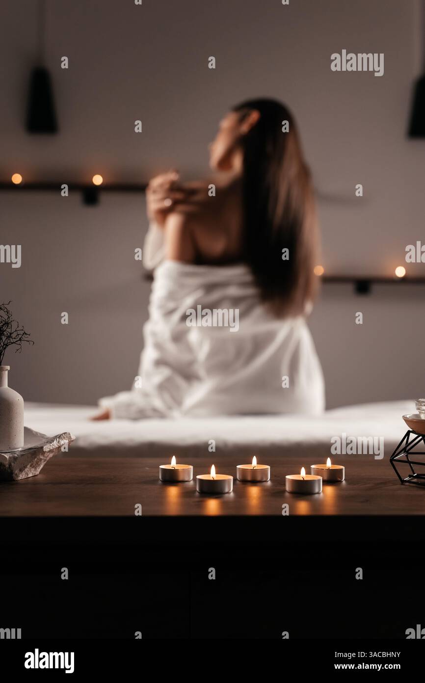 Beautiful young woman enjoying massage in spa salon. Blurred back view ...